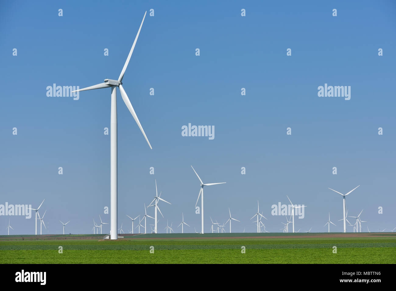 Eolian farm renewable energy in fresh green field against clear blue ...