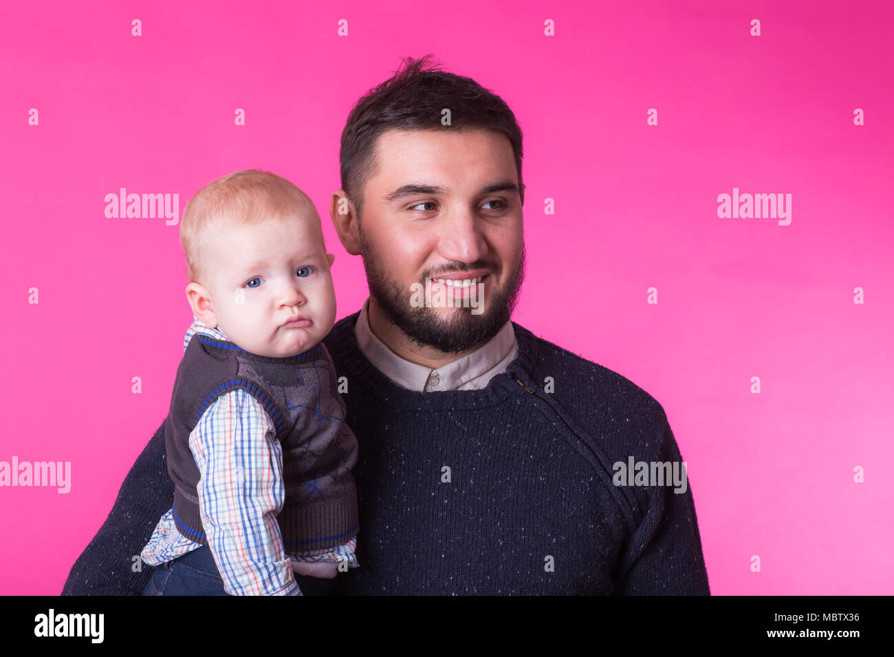 Portrait of happy father with a baby son isolated on a pink background ...