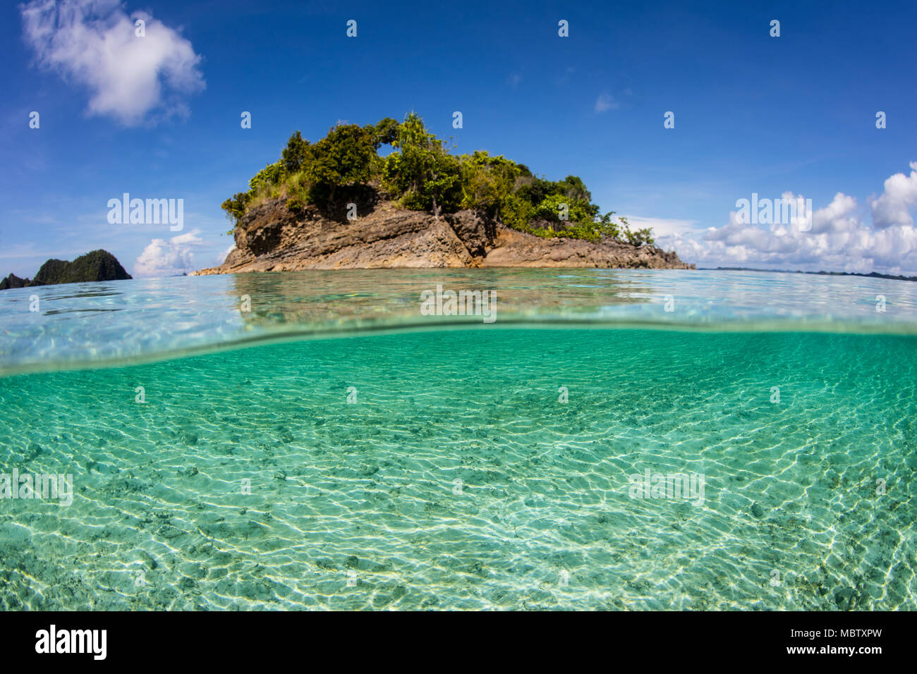 Clear, warm water covers a shallow sand flat near Misool, Raja Ampat ...