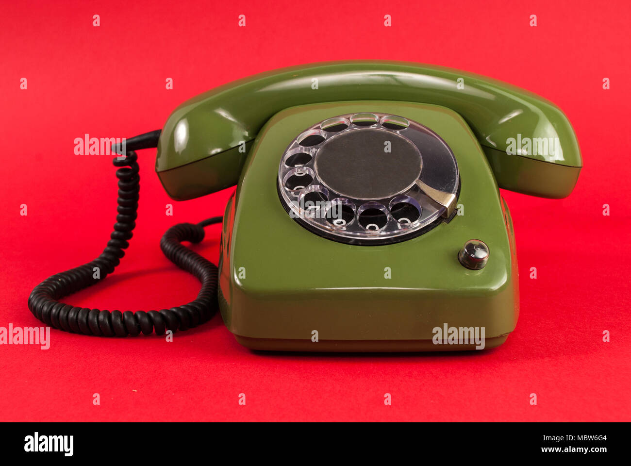 Old retro green phone on red background Stock Photo - Alamy