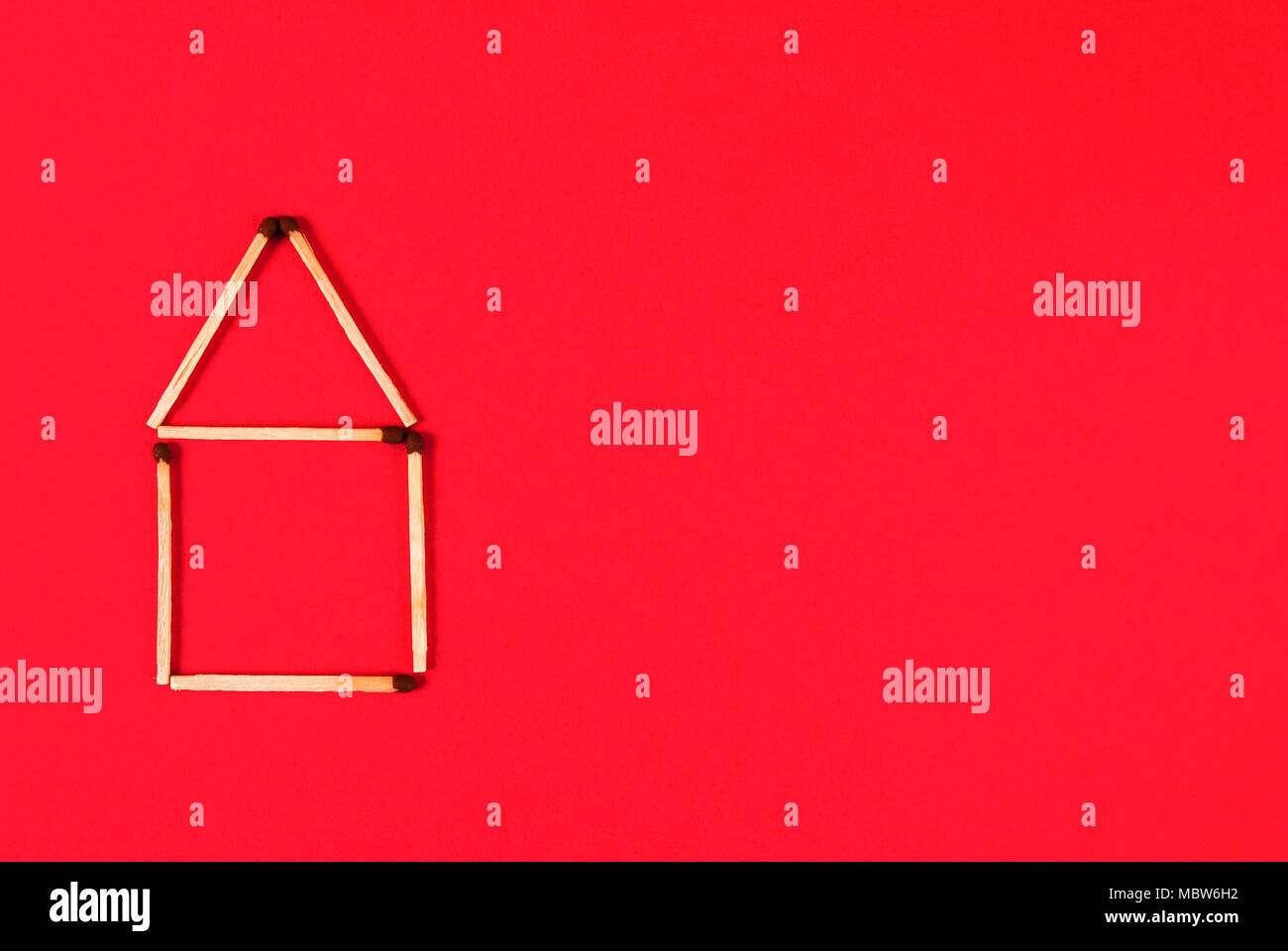 Small simple house made of matches on red background Stock Photo - Alamy