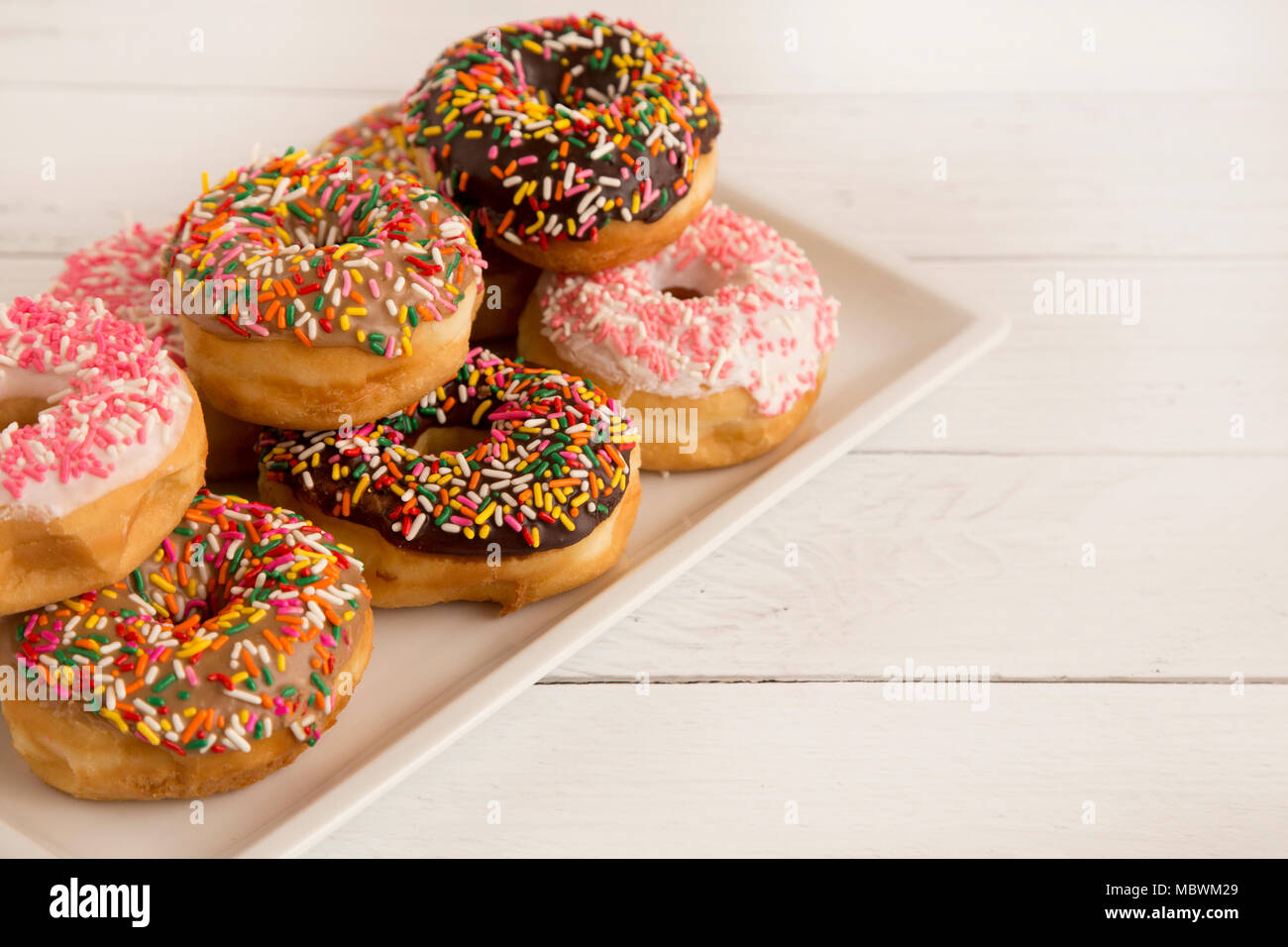 Various Flavors of Sprinkle Donuts on a White Wood Table Stock Photo ...
