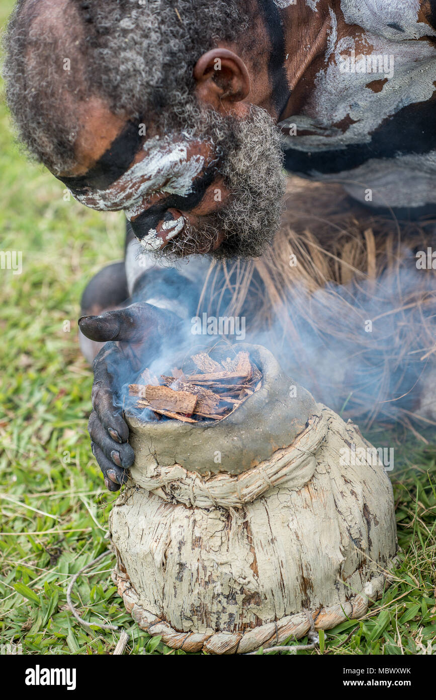 Mindima fiiremaker blowing on his headdress to revive fire, Mount Hagen ...