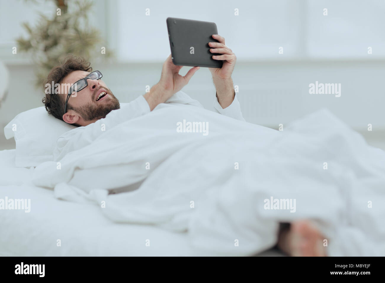 closeup.sleepy man looking at the screen of a digital tablet Stock ...