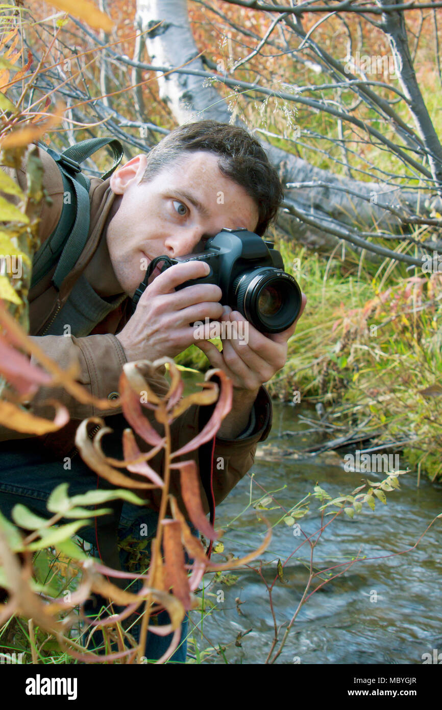 Man was inclined over a stream with camera Stock Photo - Alamy