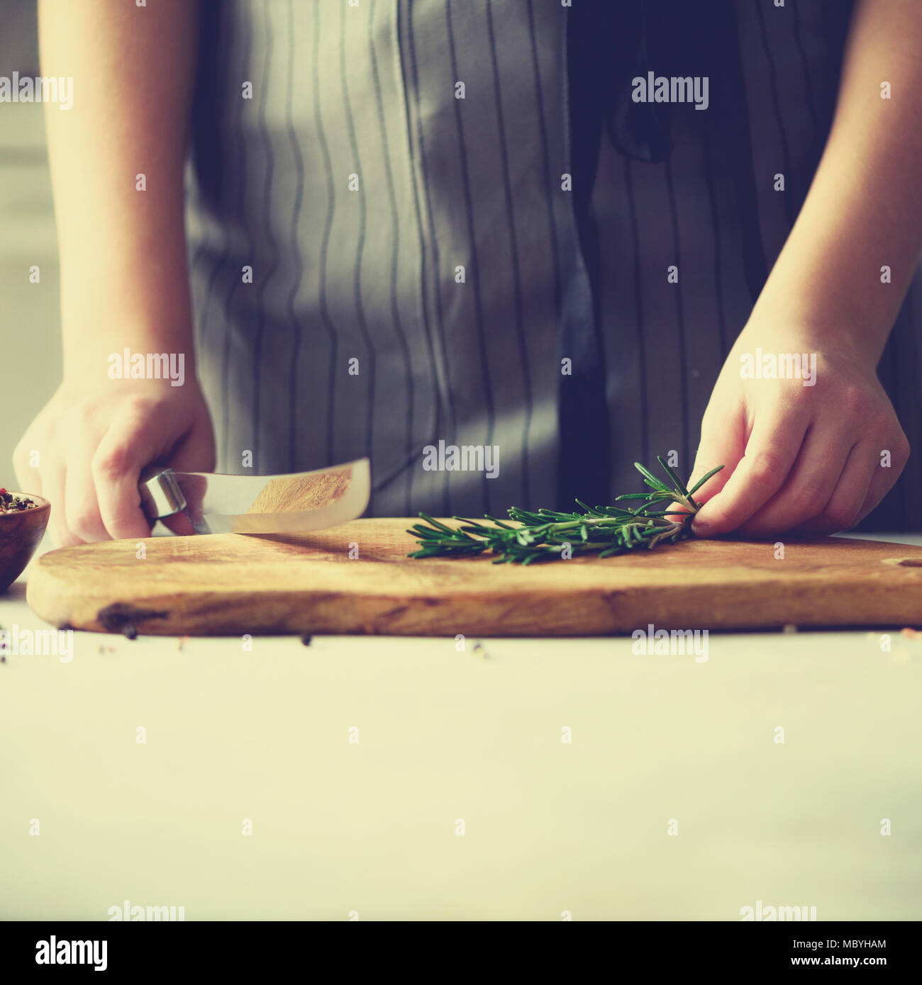 Woman hands cutting fresh green rosemary on wood chopping board in ...