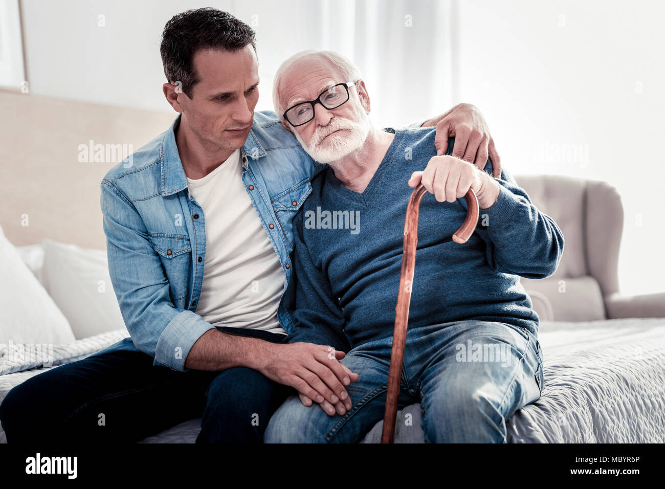 Nice thoughtful father and son sitting together Stock Photo - Alamy