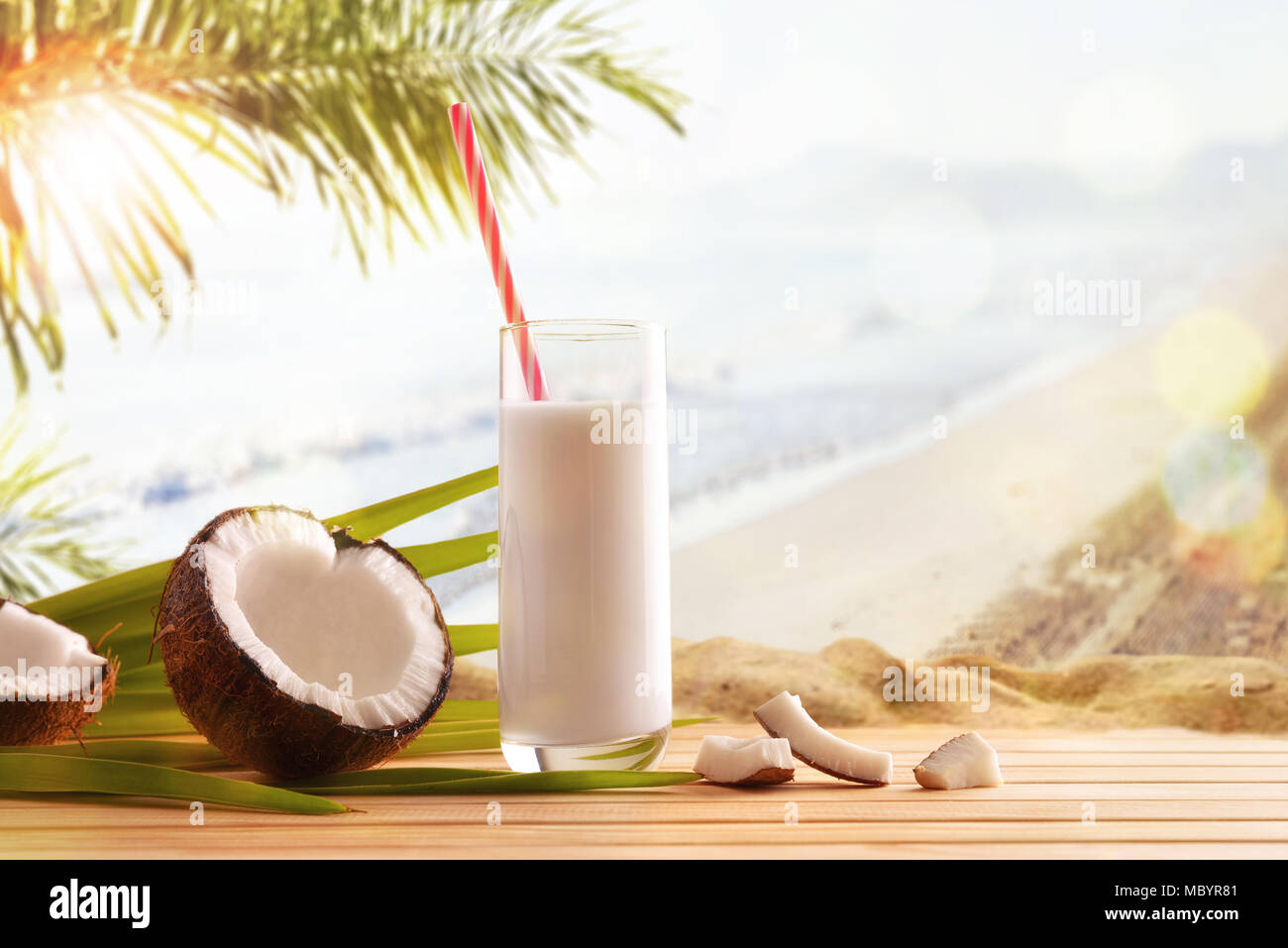 Coconut drink in glass with fruit on wooden table on tropical beach ...