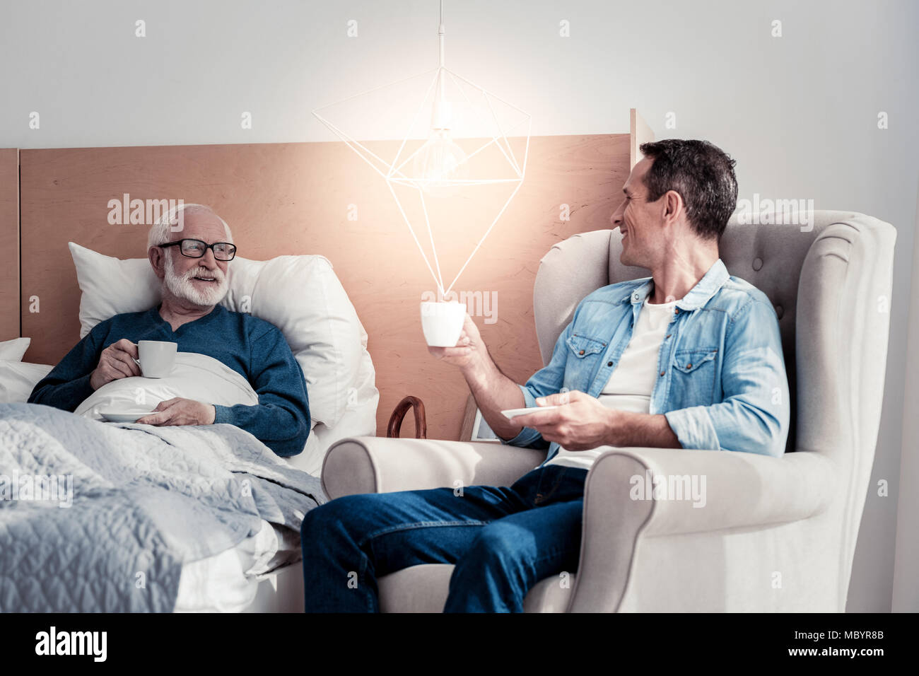 Joyful positive father and son having tea Stock Photo - Alamy