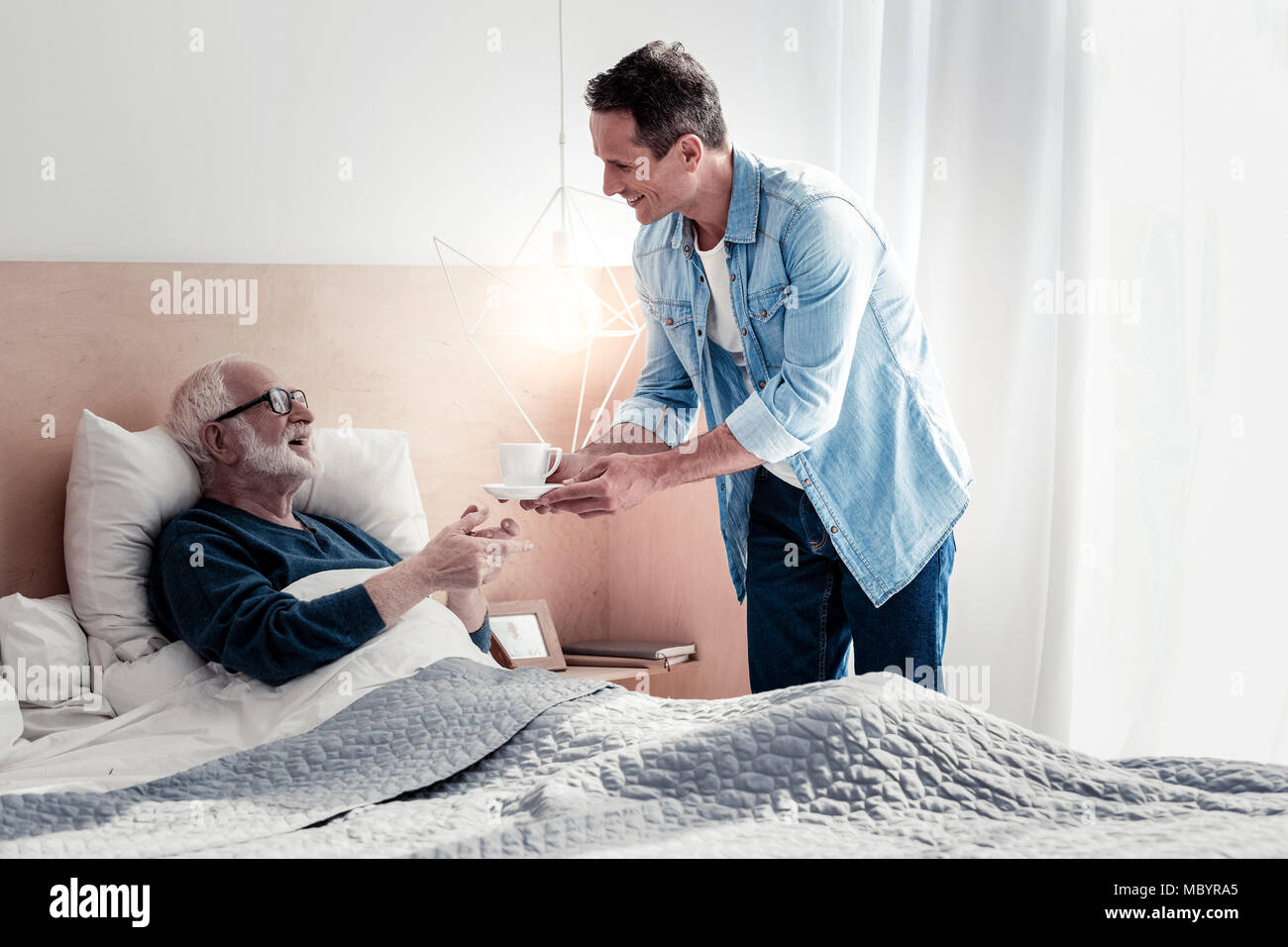 Nice young man bringing his father tea Stock Photo - Alamy