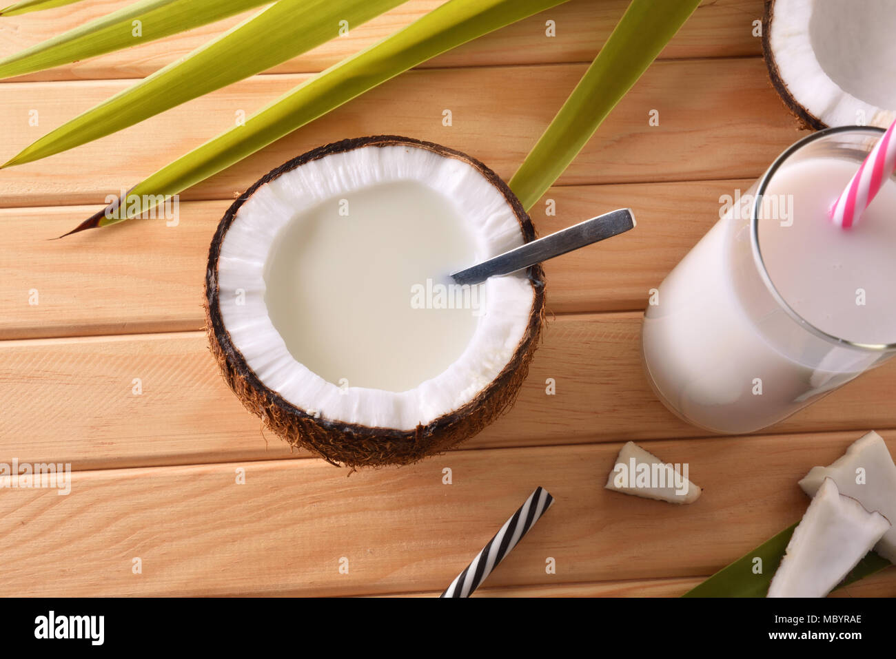 Coconut milk in containers with coconut fruit on wooden table ...