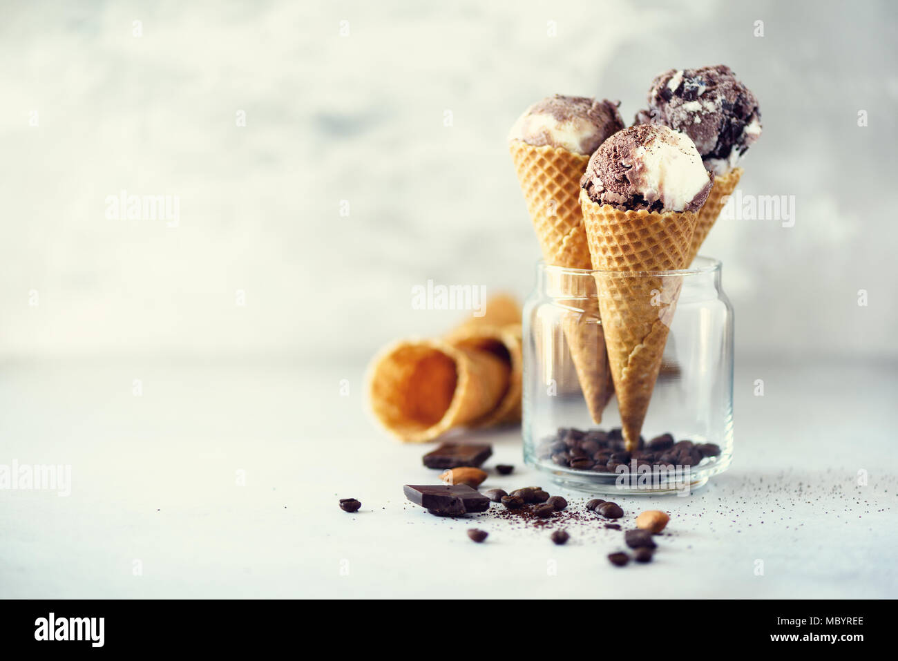 Chocolate and coffee ice cream in waffle cone with coffee beans on grey ...