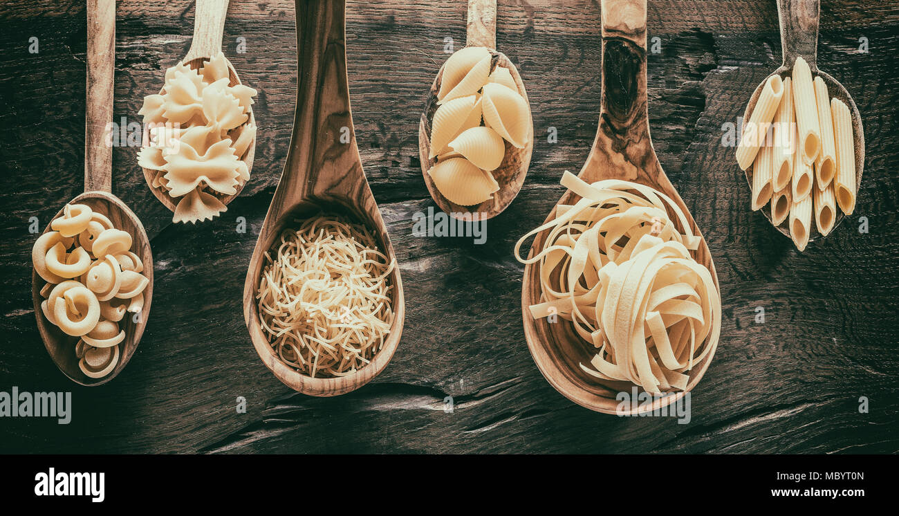 Different pasta types in wooden spoons on the table Stock Photo - Alamy