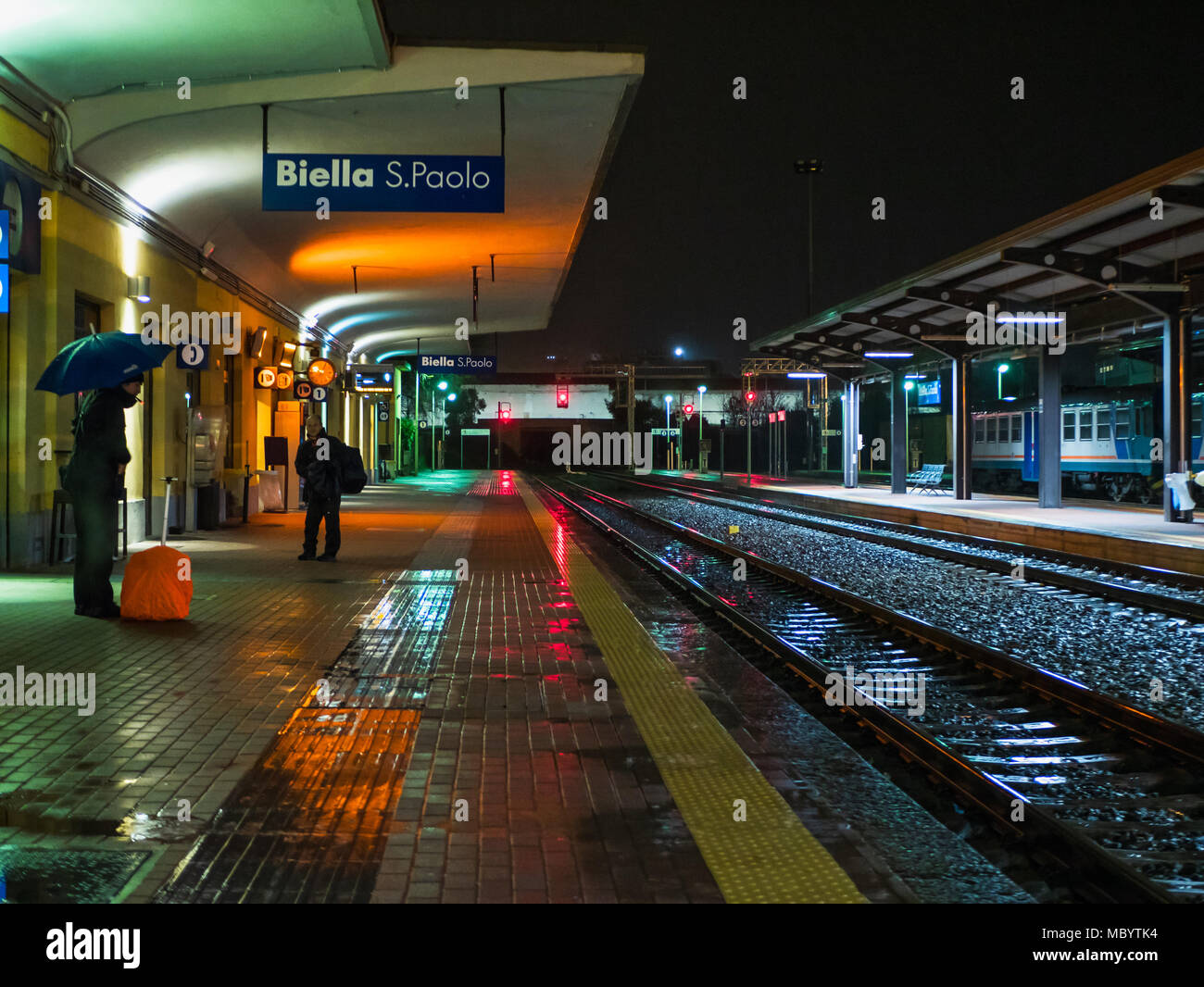 Two train drivers in station, on a rainy night. Wet rails in the rain ...