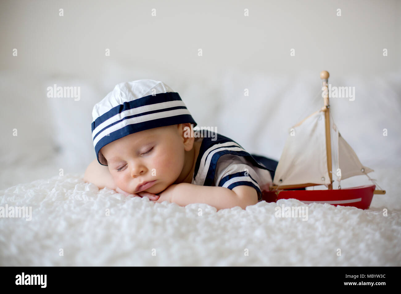 Cute baby boy, dressed in sailor clothes, sleeping with wooden boat and ...