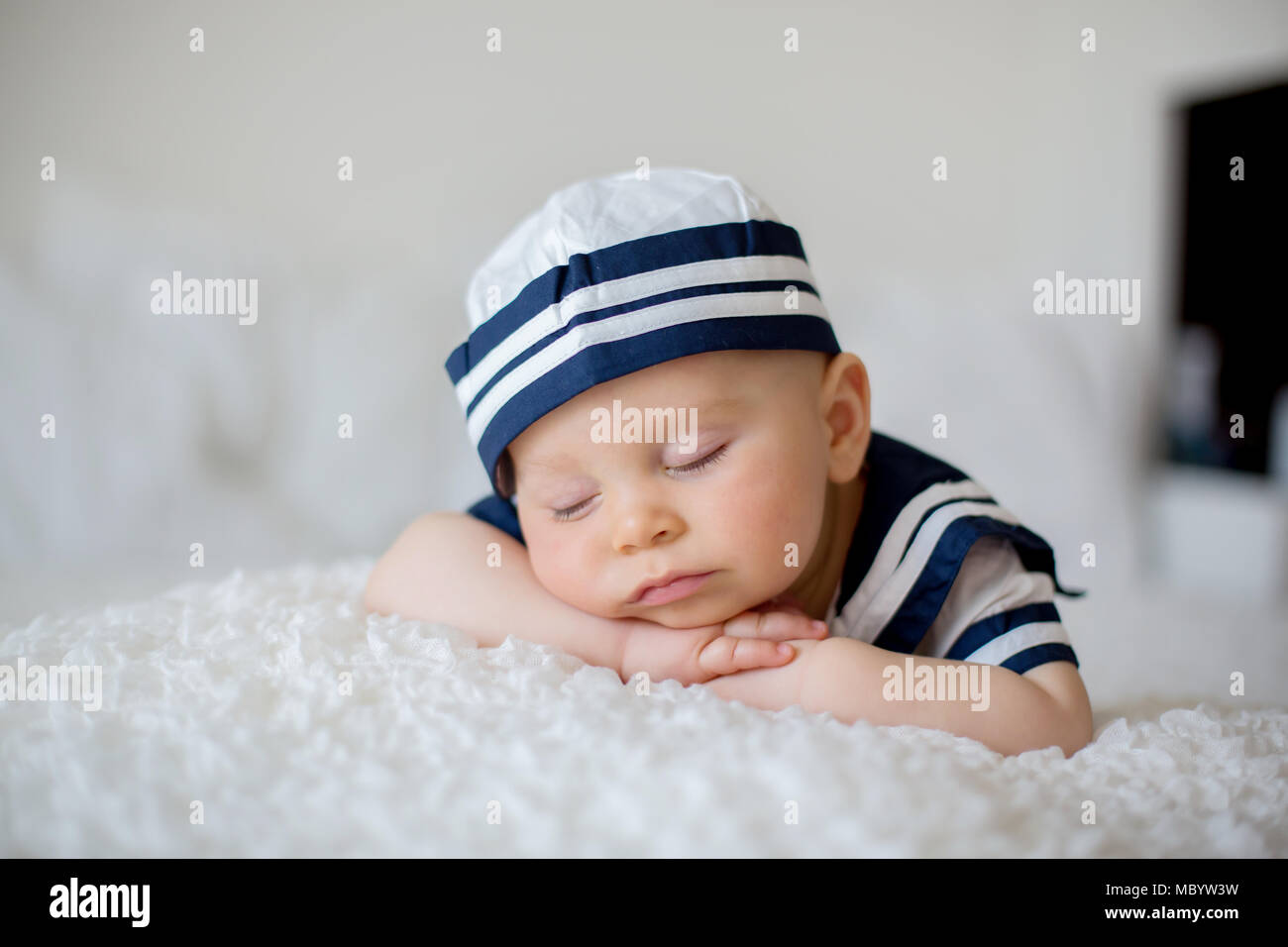 Cute baby boy, dressed in sailor clothes, sleeping with wooden boat and ...