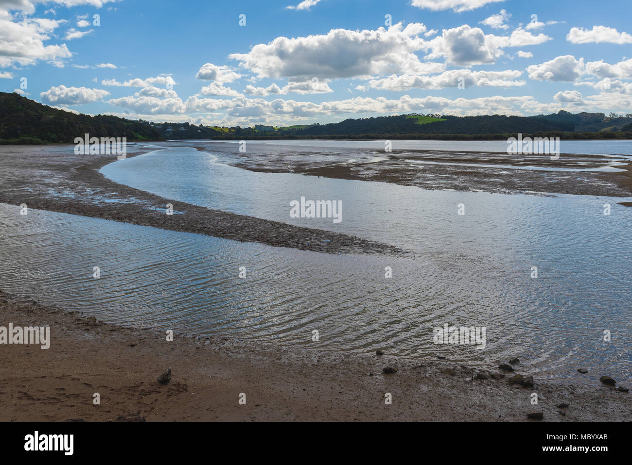 Exposed sand banks of a beach at low tide under a blue cloudy sky in ...