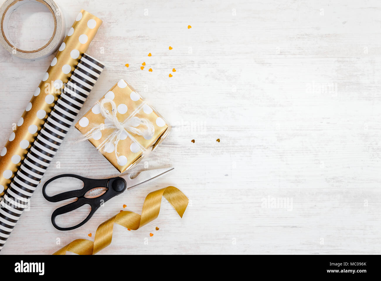 Gift box wrapped in golden dotted paper and wrapping materials on a ...