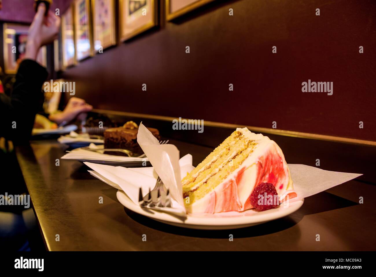 Close up of various slices of cakes served at a bar counter. People ...