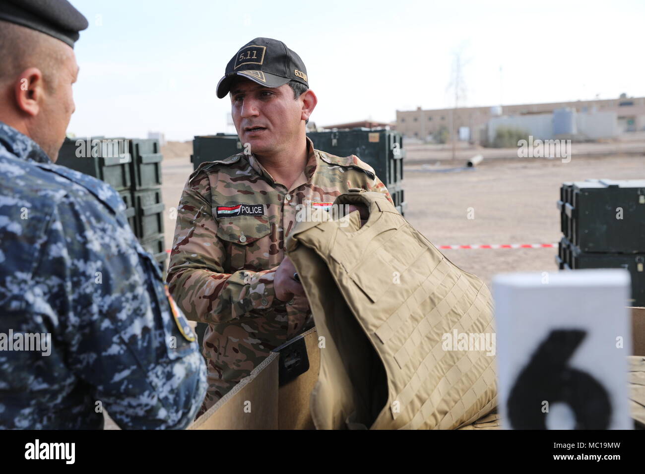 Members of the Iraqi Police look at one ballistic vest from a container ...