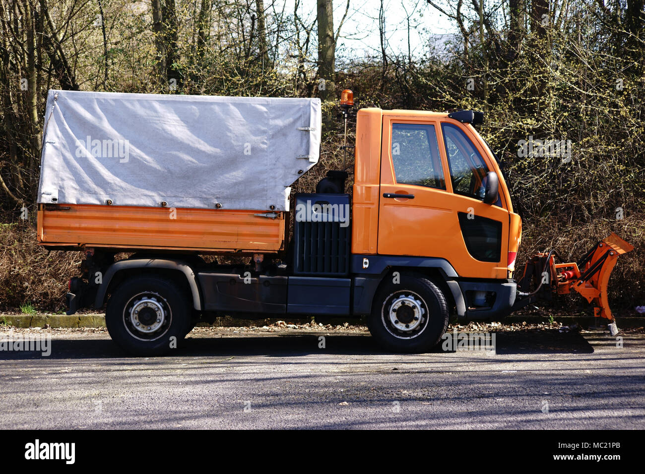 The side view of a small clearing vehicle with plow and loading area ...