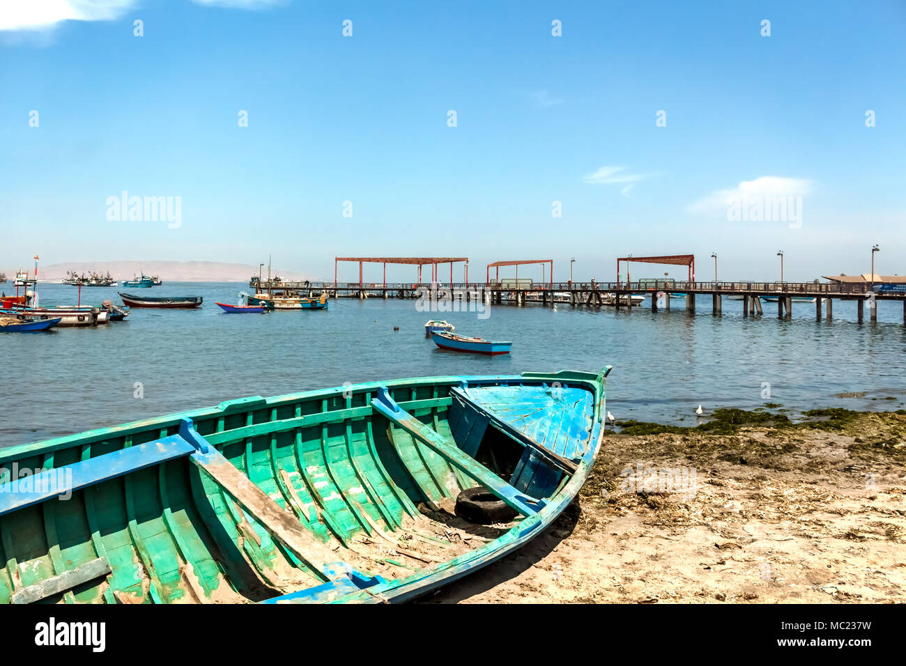 relict of a colorful and old fishing boat on the beach with a pier ...