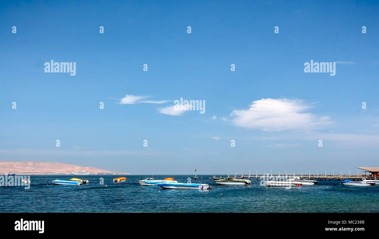 colorful boats with pier stretching into the horizon in the pacific ...