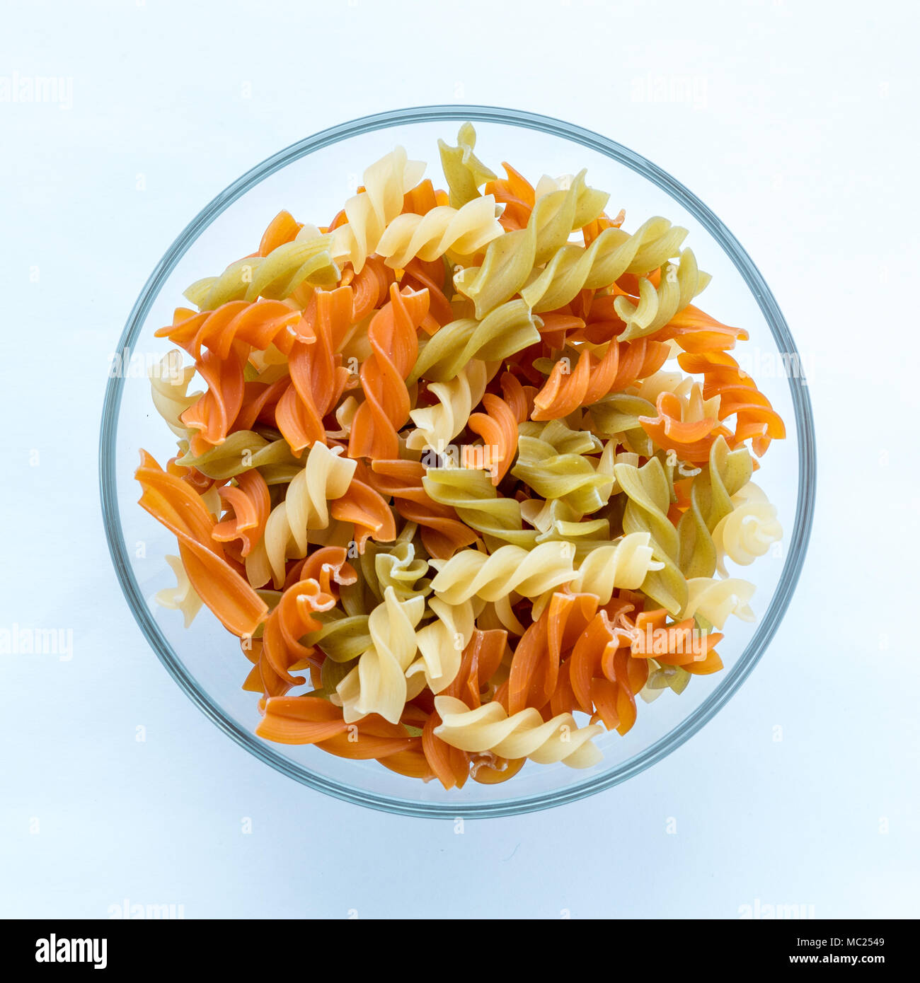 Multicolor spiral macaroni pasta in glass bowl on white isolated ...