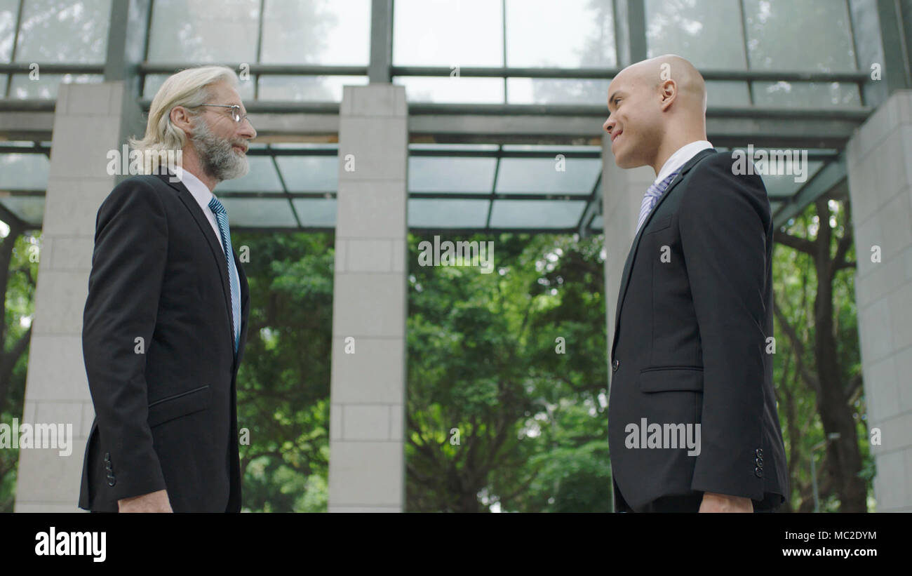 two corporate business people standing and talking in lobby of modern ...
