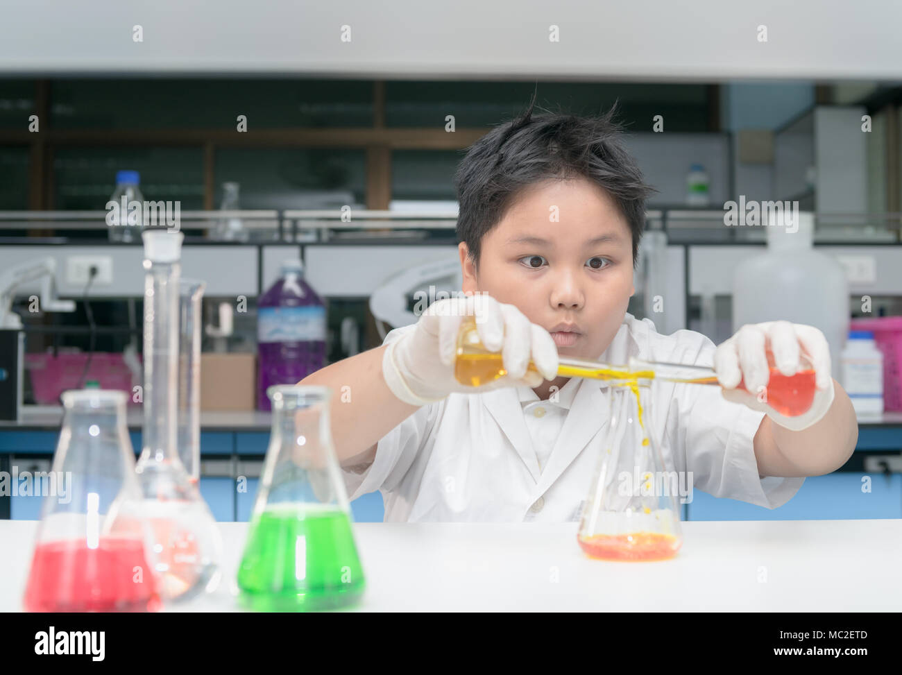 kid scientist in lab coat making experiment with test tube in chemical ...