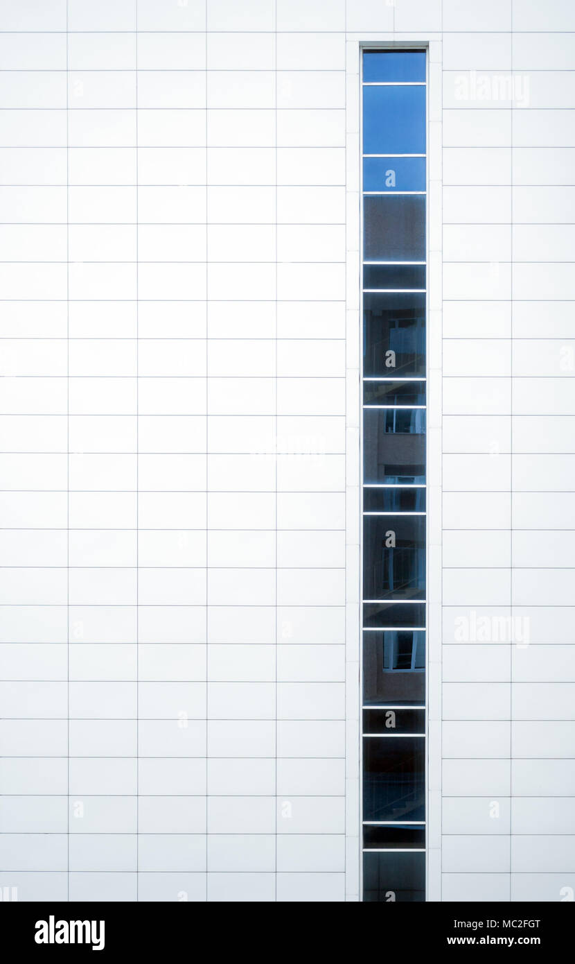 White tiles lined facade of modern building with narrow blue windows ...