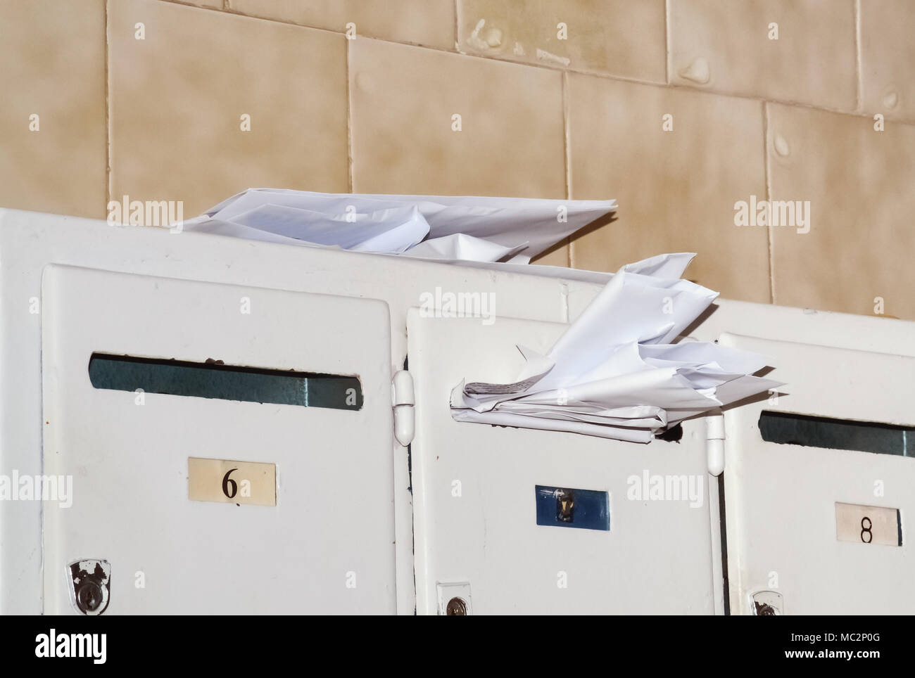 Closeup of several letter boxes one of which is full of bills and ...