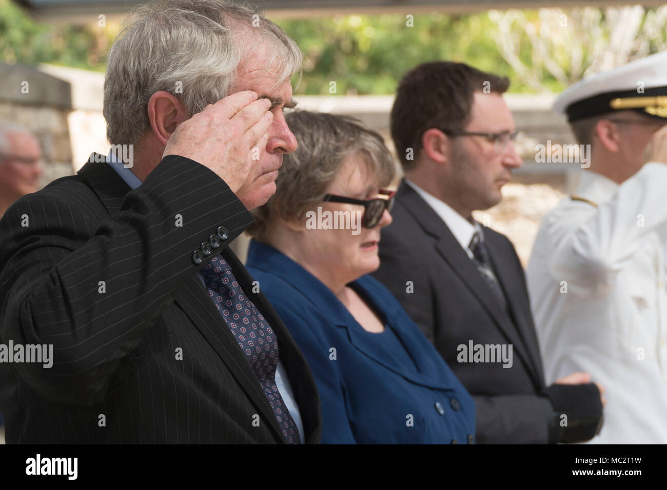 A family member renders a salute while U.S. Sailors assigned to Navy ...