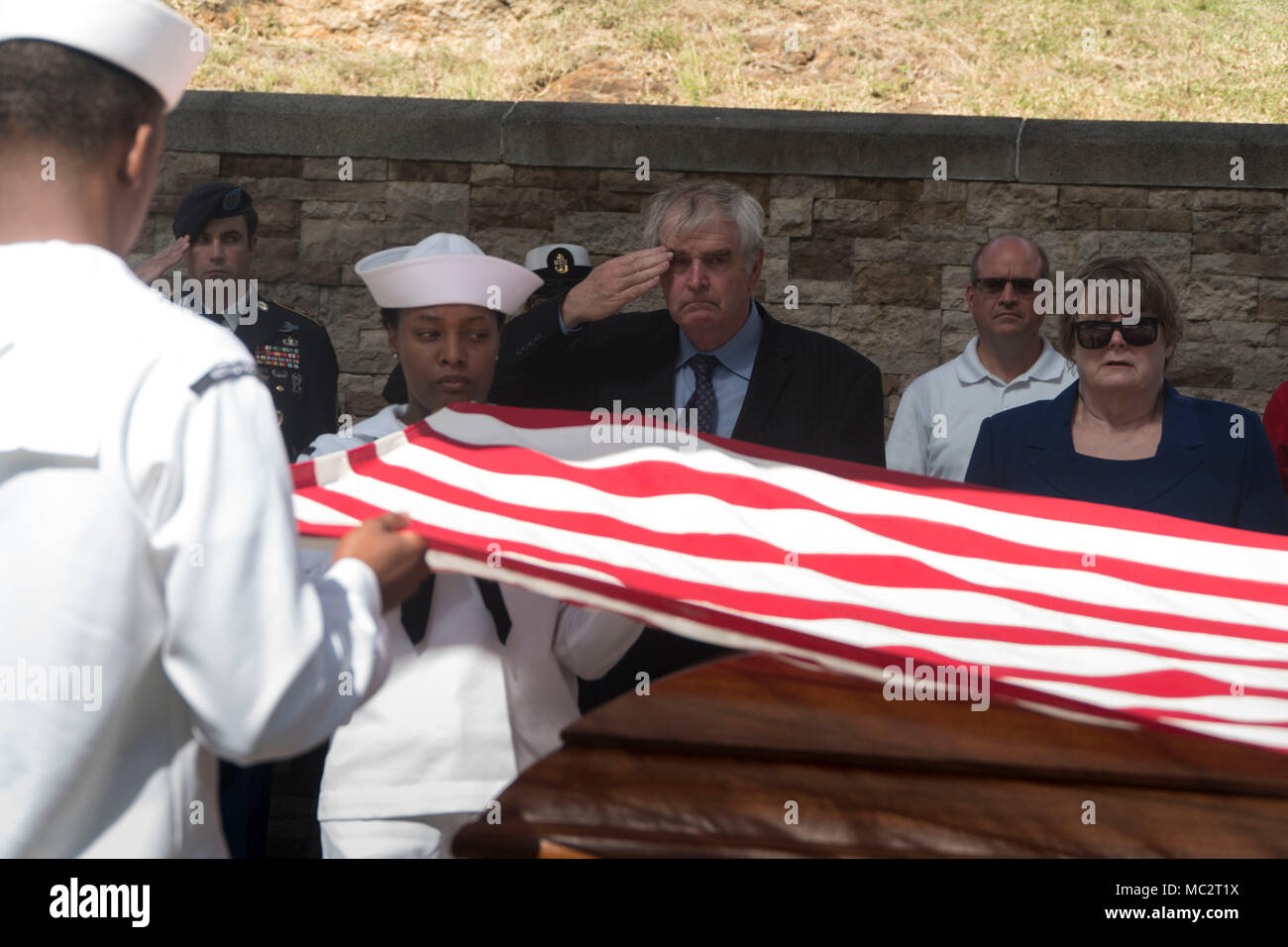 A family member renders a salute while U.S. Sailors assigned to Navy ...