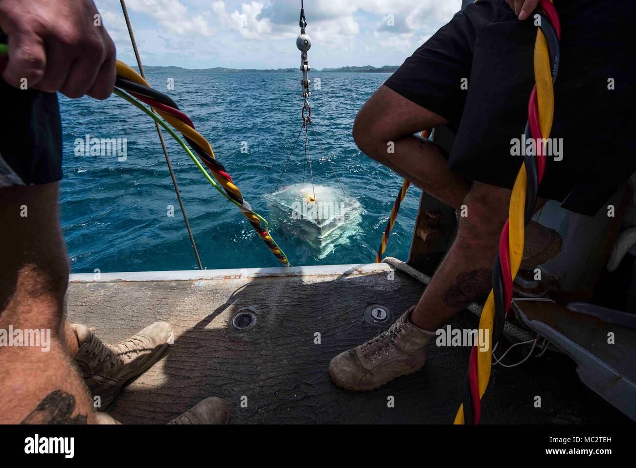U.S. Navy divers assigned to Mobile Diving and Salvage Unit One, lower ...