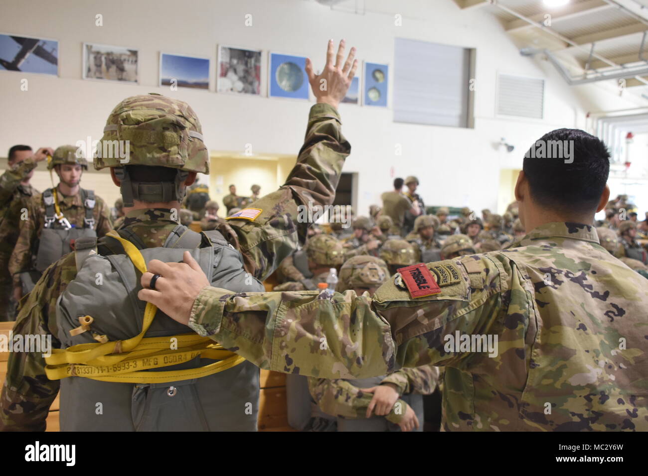 A paratrooper calls for a rigger as the jumpmaster who is inspecting ...