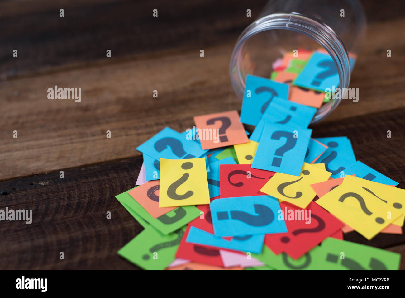 colorful paper with question mark in a plastic jar on wooden table ...