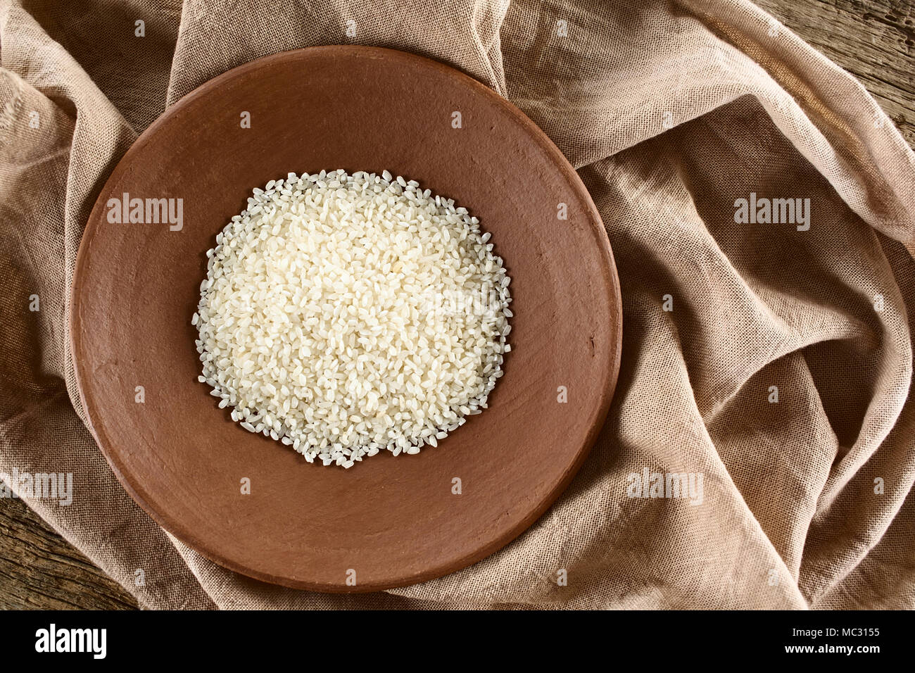 Raw arborio risotto short-grain rice on clay plate, photographed ...