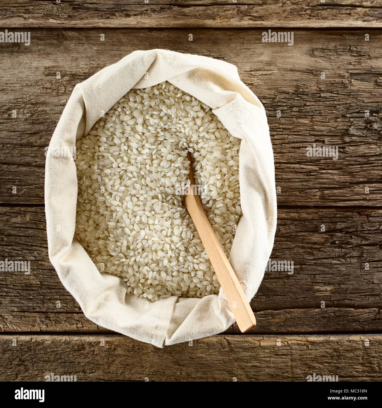 Raw arborio risotto short-grain rice in bag with wooden spoon ...