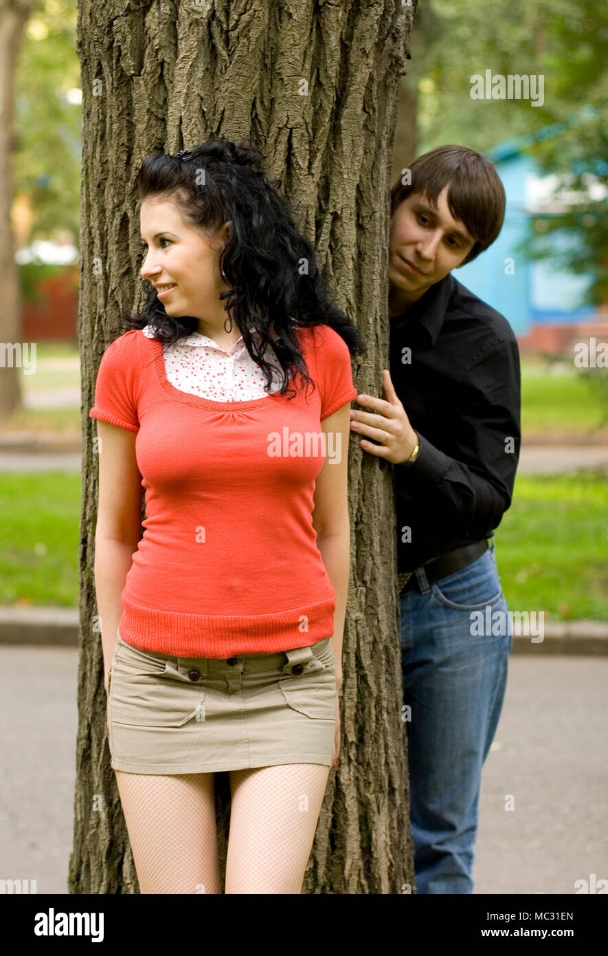 pretty woman and a man hiding behind a tree Stock Photo - Alamy