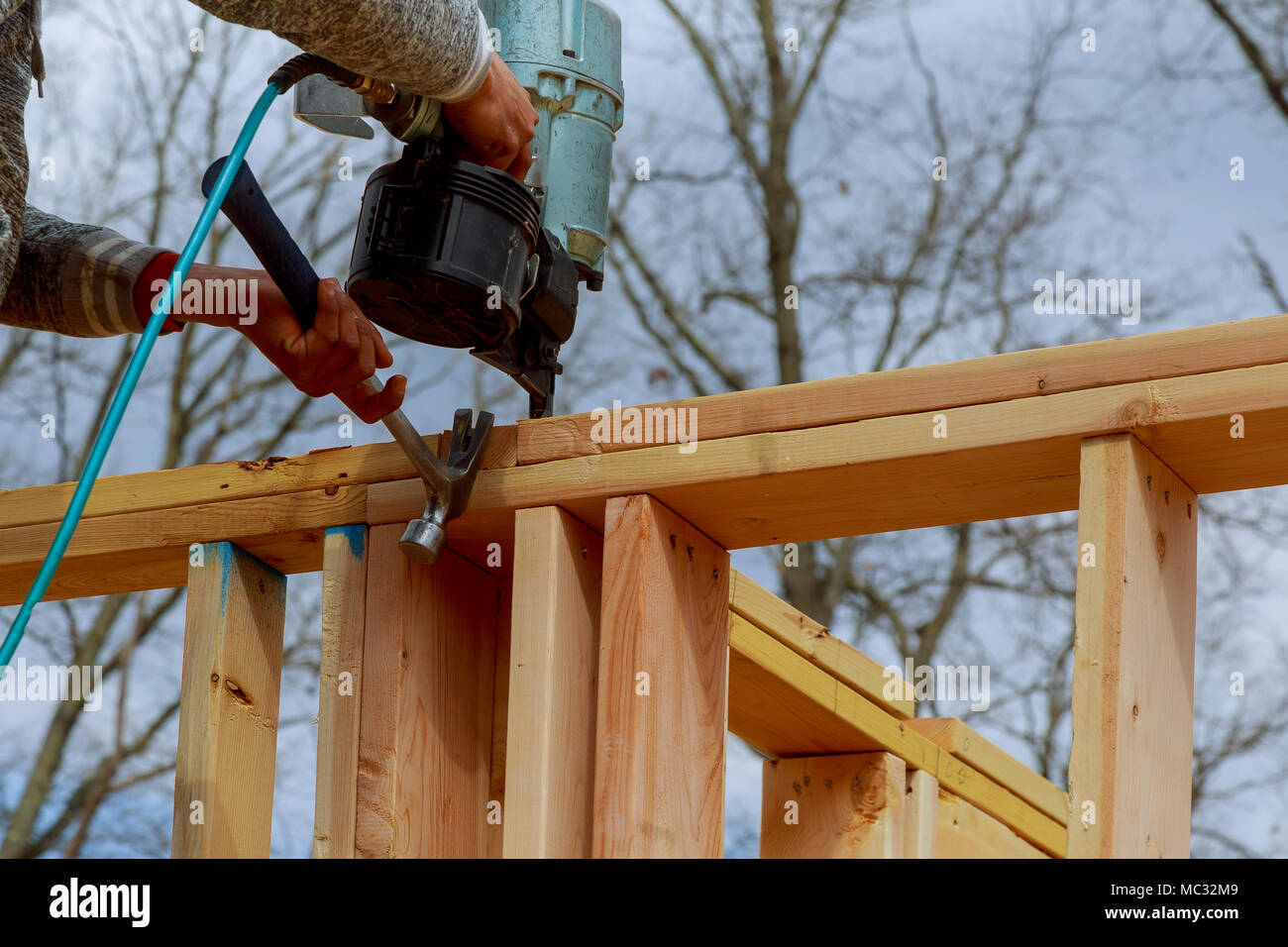 Authentic construction worker framing building contractor using nail ...