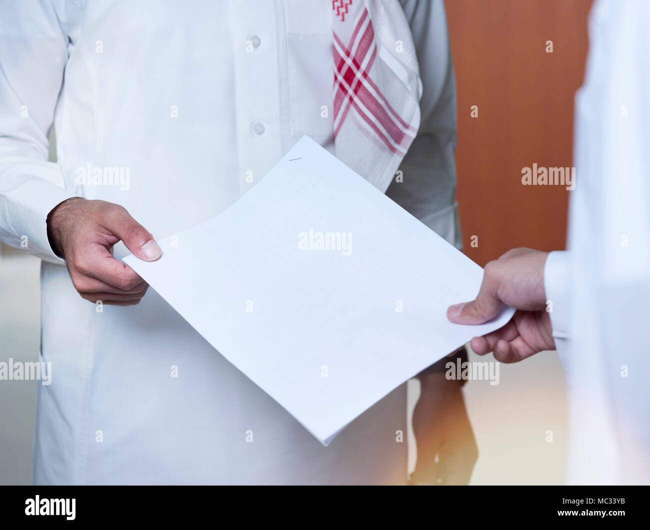 Saudi Businessman handing over a paper document to a fellow employee ...