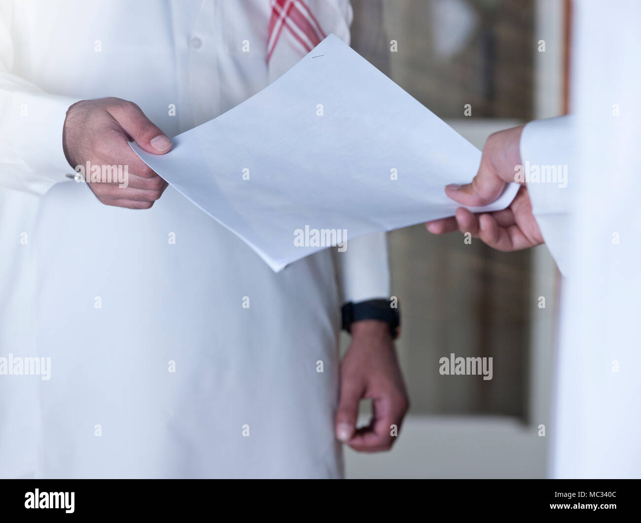 Saudi Businessman handing over a paper document to a fellow employee ...
