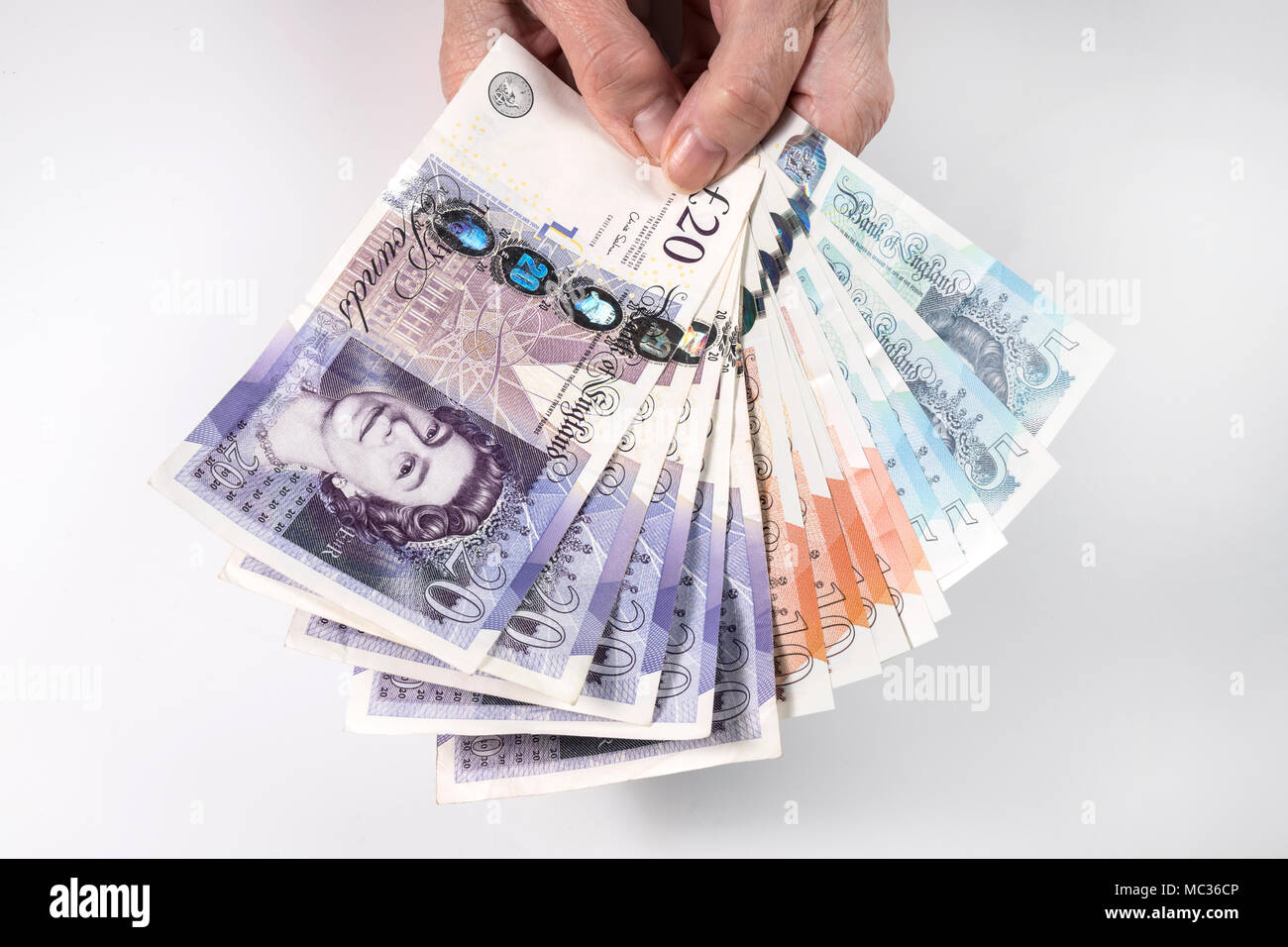 A female hand holding UK money, £5 pound, £10 pound and £20 pound notes ...