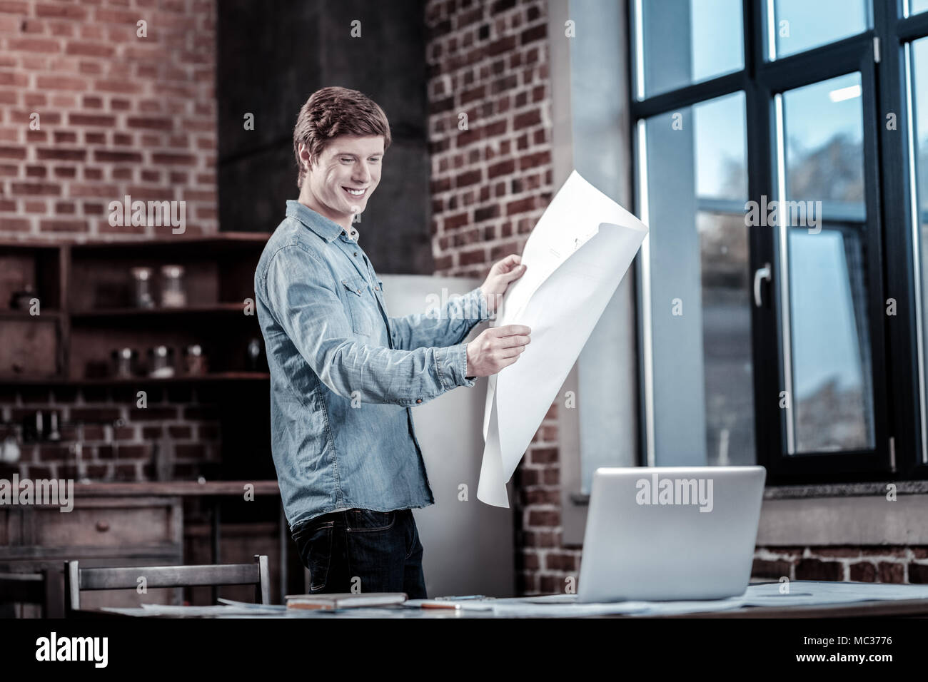 Joyful male engineer comparing blueprints Stock Photo - Alamy