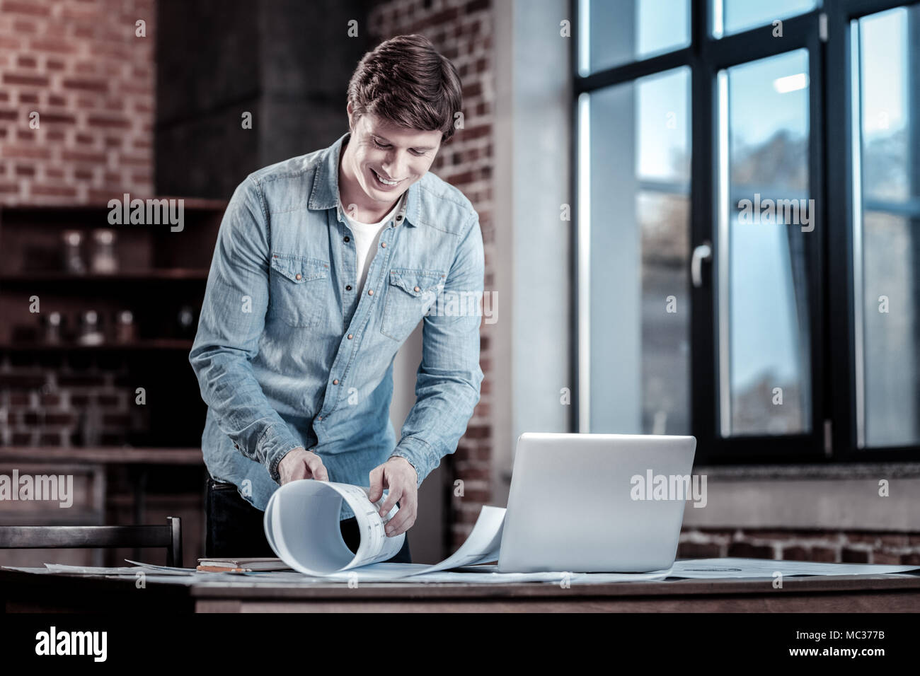 Successful male engineer packing blueprint Stock Photo - Alamy