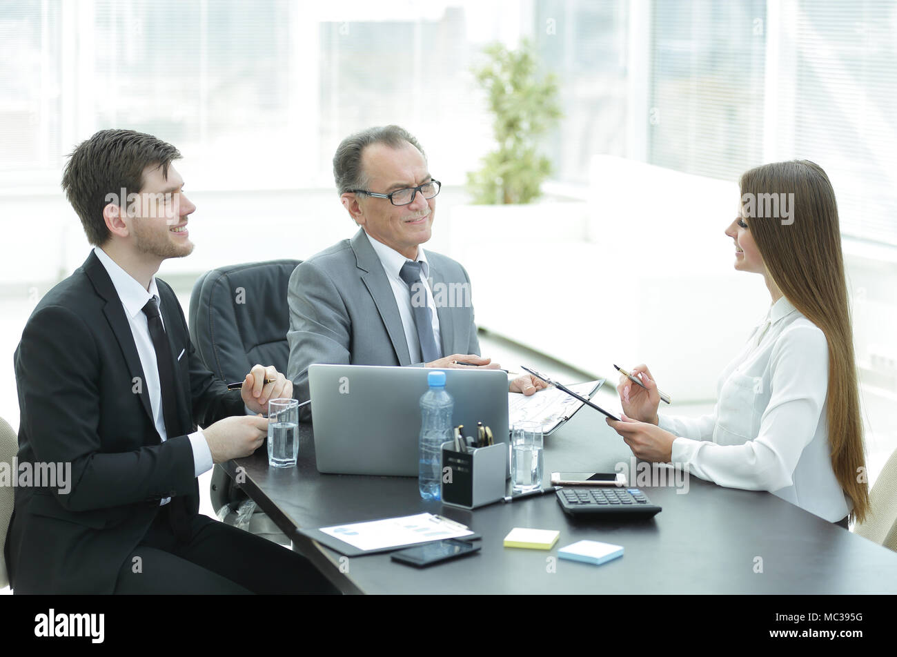 Manager discussing work issues with his assistants behind a Desk Stock ...
