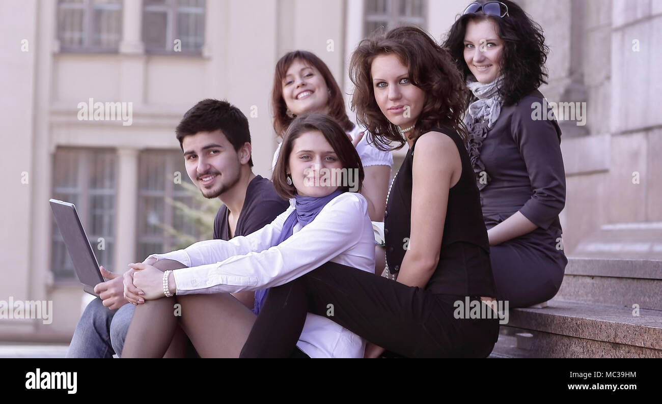 portrait of a group of students sitting in front of the University ...