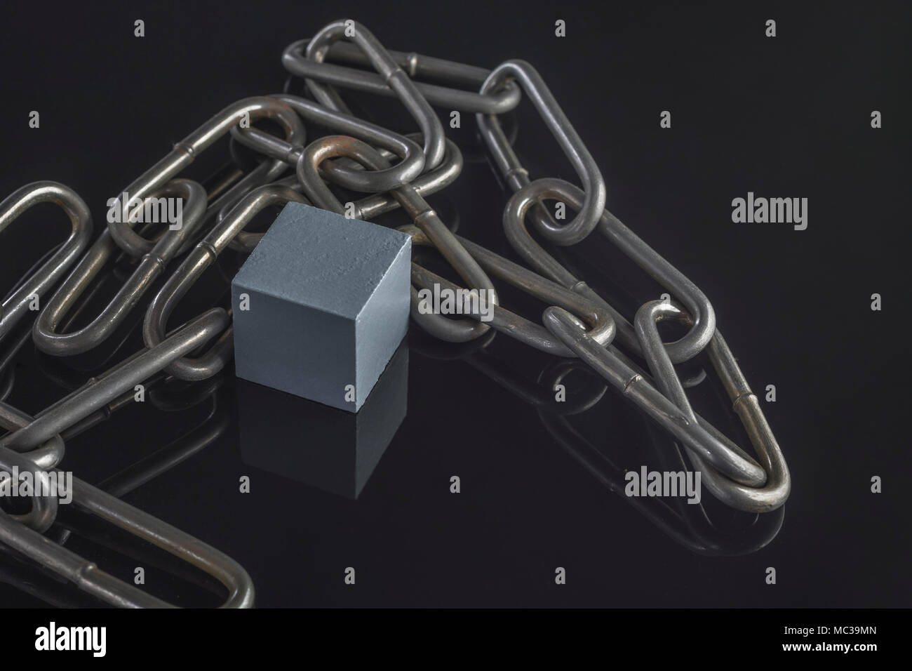 Macro-photo of small grey cube with metal chain - metaphor for concept ...