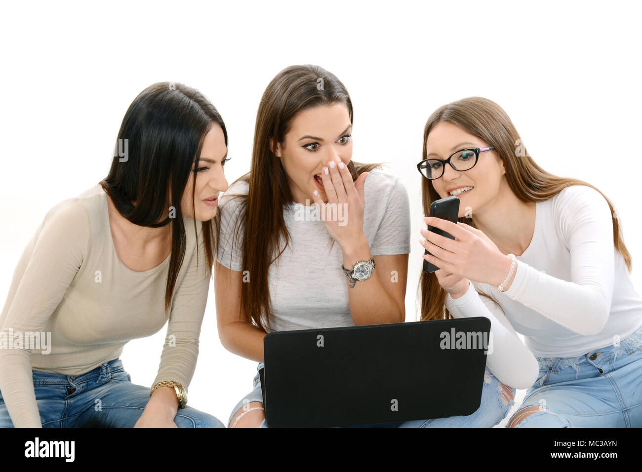 Group of three girls laughing while watching the laptop and smart phone ...